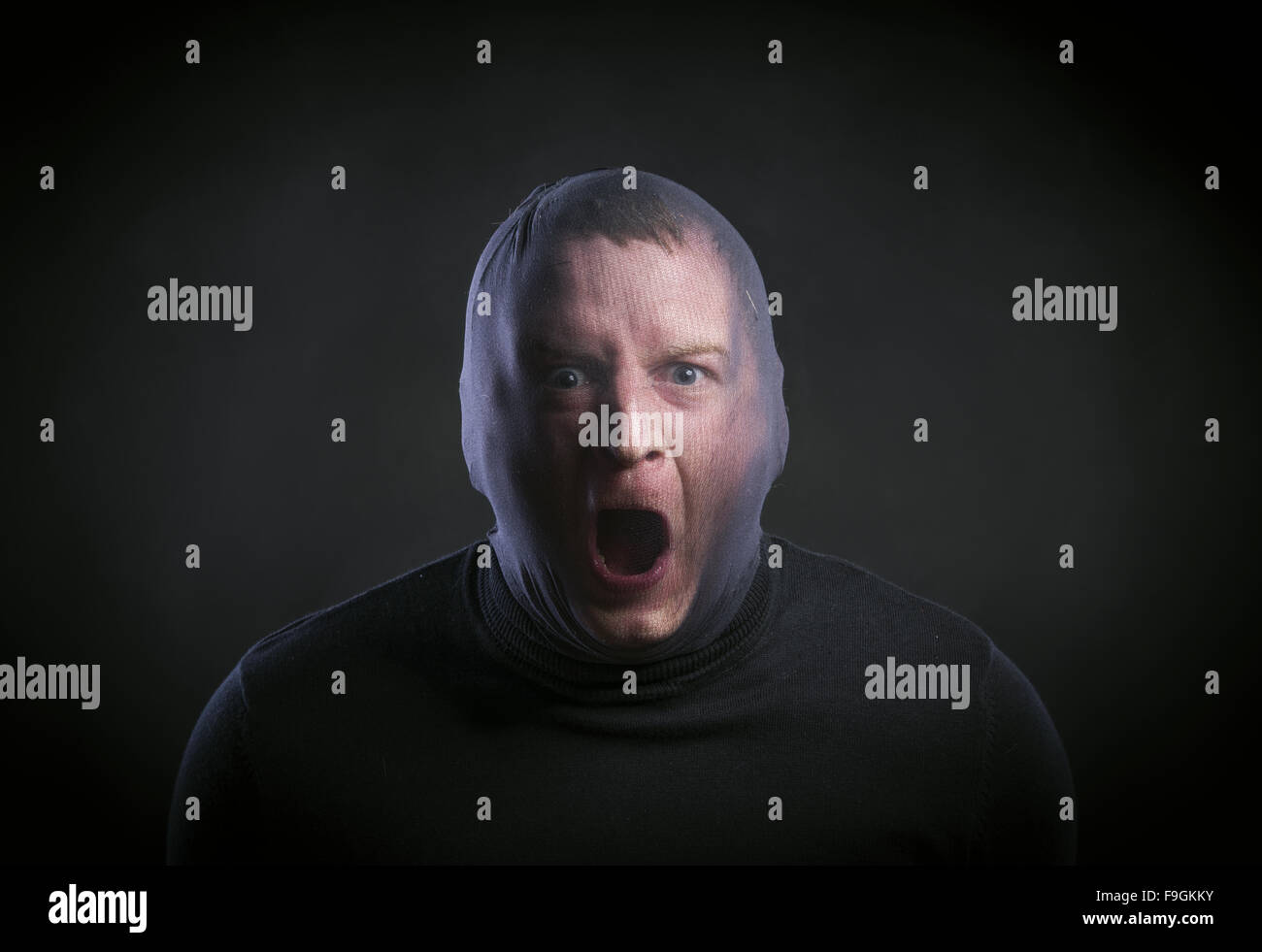 Thief in action with balaclava on his face, dressed in black. Studio ...