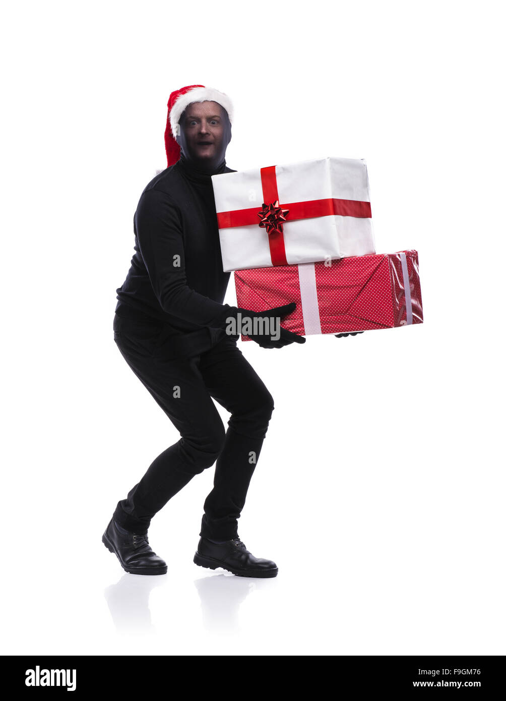 Thief in action carrying presents with balaclava on his face, dressed ...