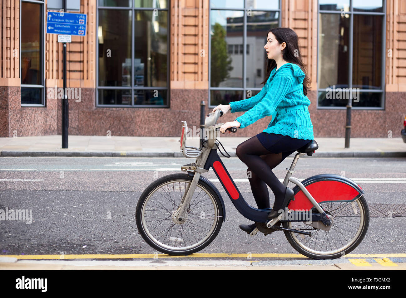 young woman riding a hire bike in the street Stock Photo - Alamy