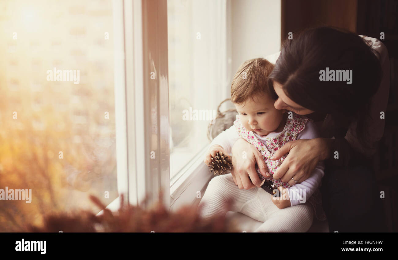 Mother with her baby daughter by the window Stock Photo - Alamy