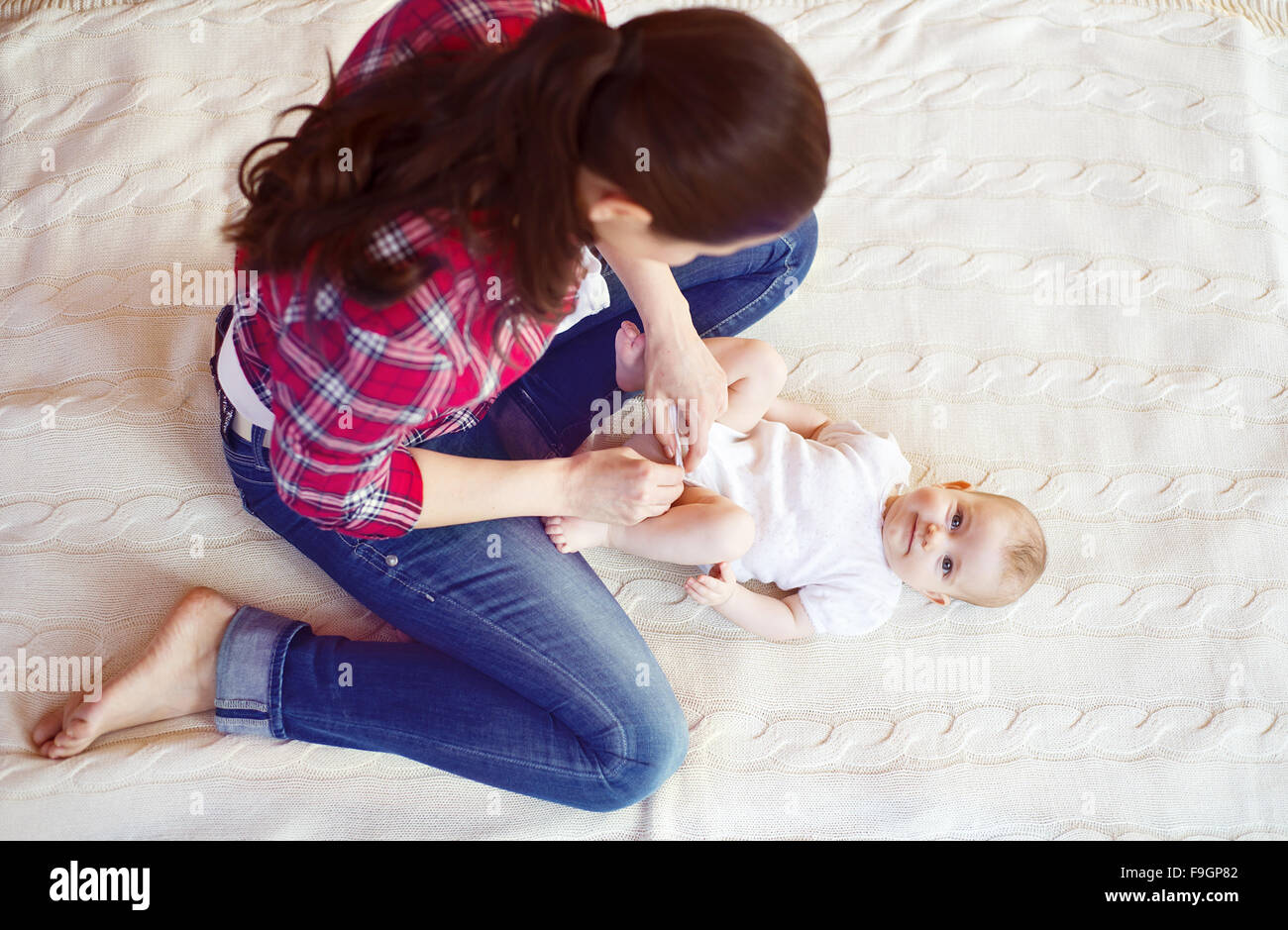 Cute little baby girl getting dressed by her mother on a carpet in a ...