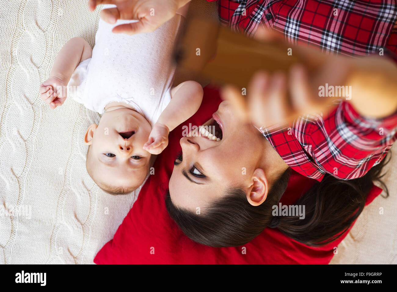 Cute little baby girl and her mother taking selfie on a blanket in a ...