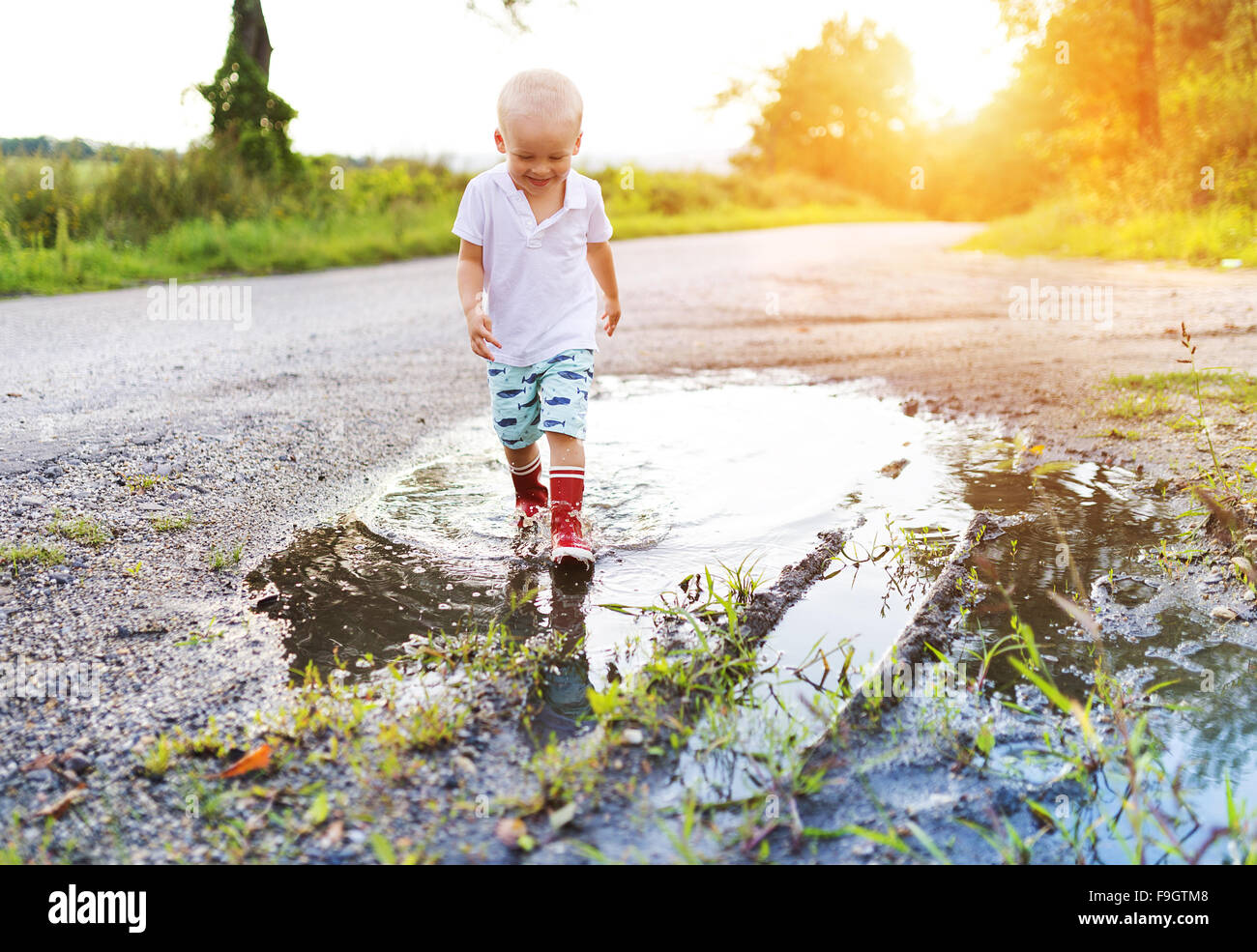 Little boy playing outside in a puddle Stock Photo - Alamy