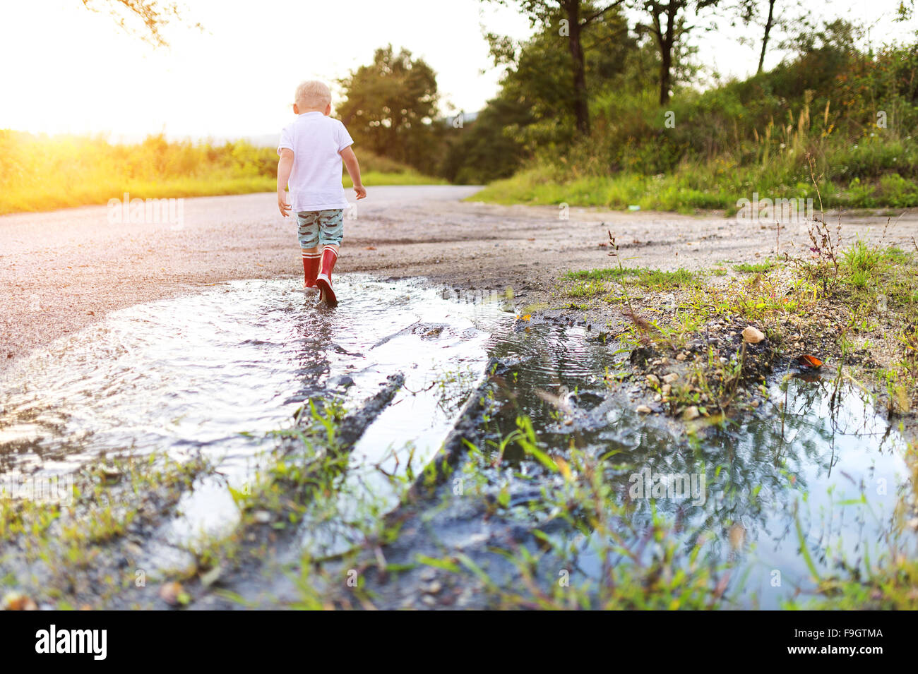 Little boy playing outside in a puddle Stock Photo - Alamy