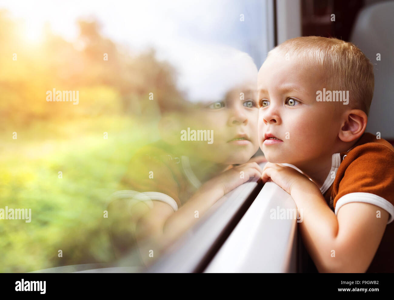 Little boy traveling in train looking outside the window Stock Photo ...