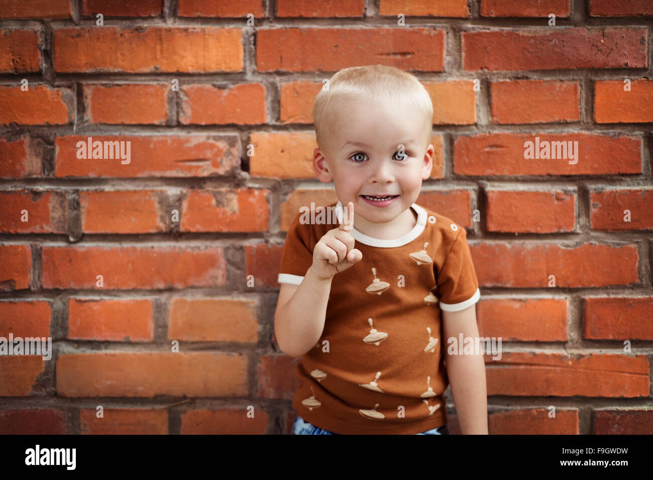 Cute little boy making funny faces on a brick wall background Stock ...