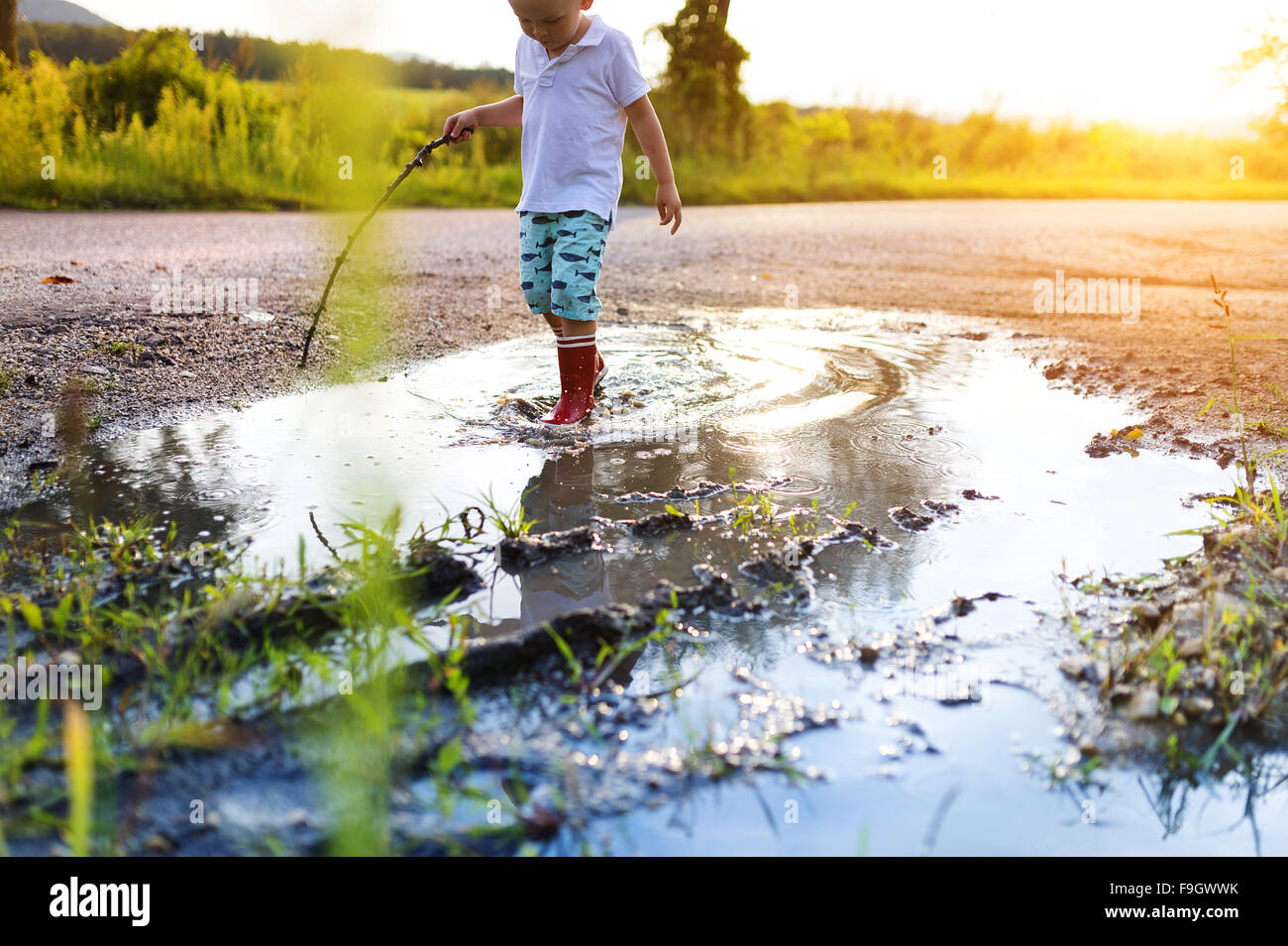 Little boy playing outside in a puddle Stock Photo - Alamy