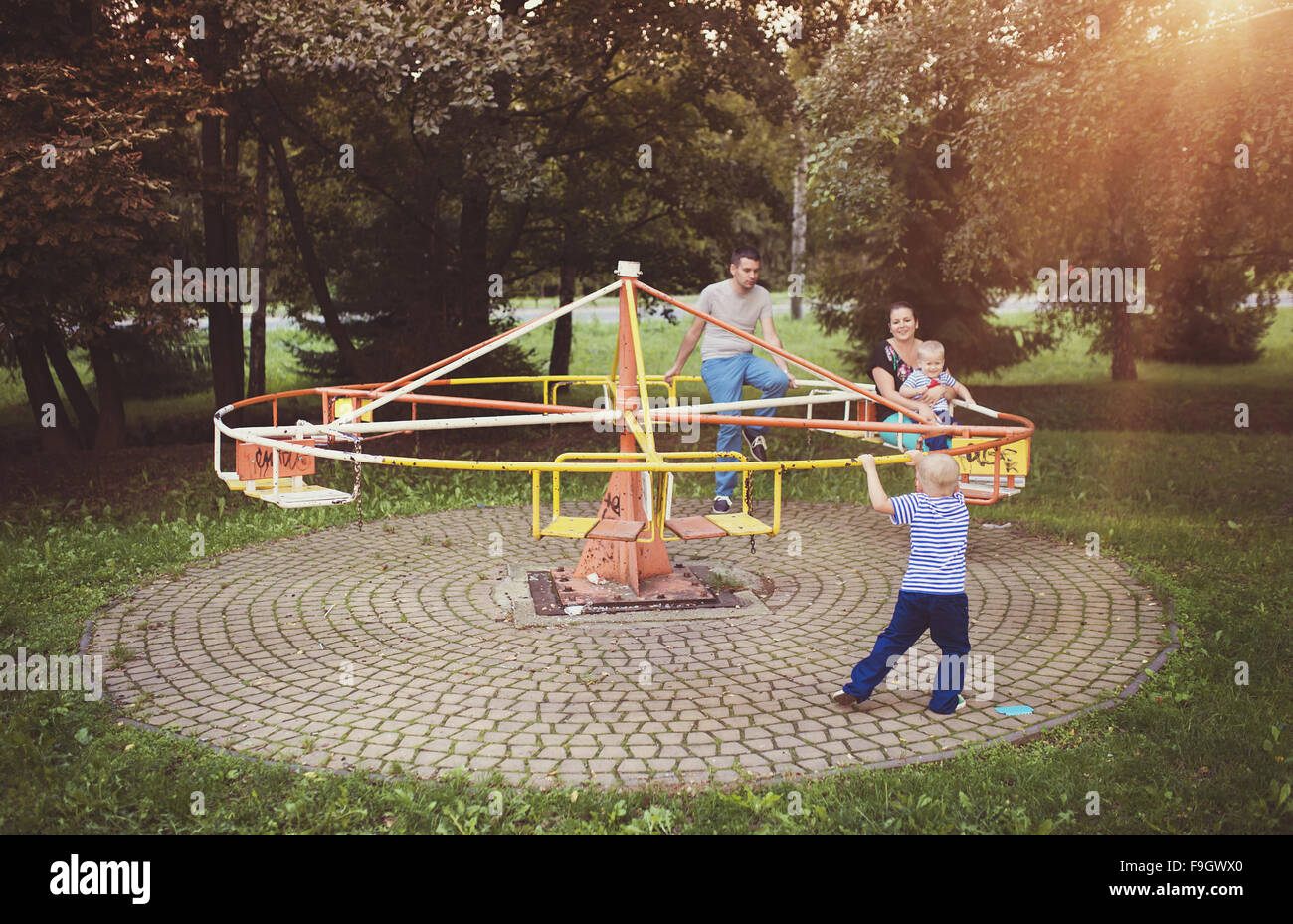 Happy family outside in a park on an old carousel Stock Photo - Alamy