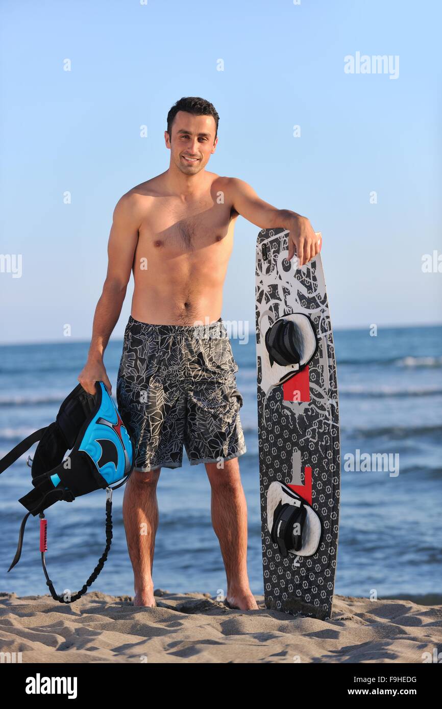 Portrait of a strong young surf man at beach on sunset in a ...