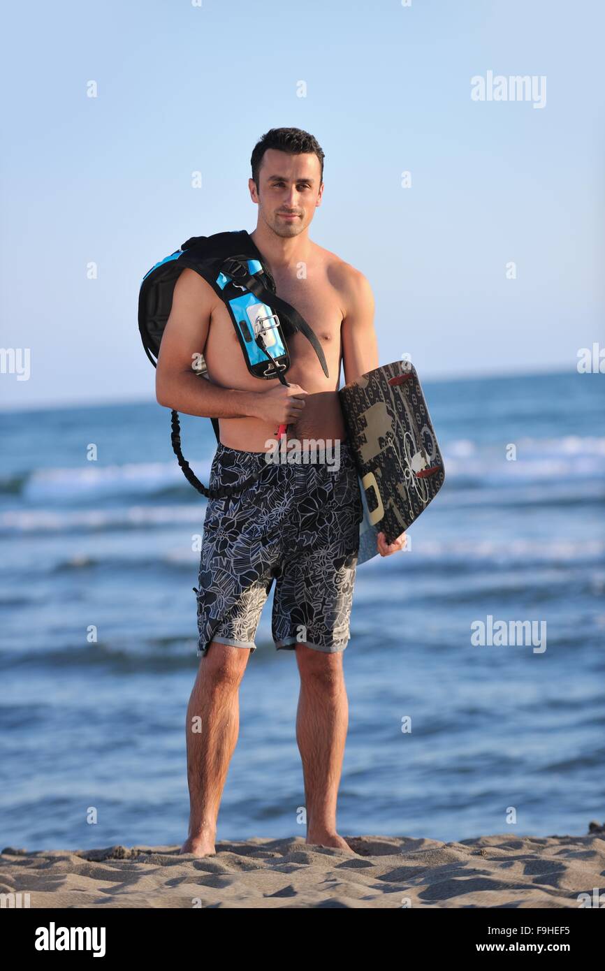Portrait of a strong young surf man at beach on sunset in a ...