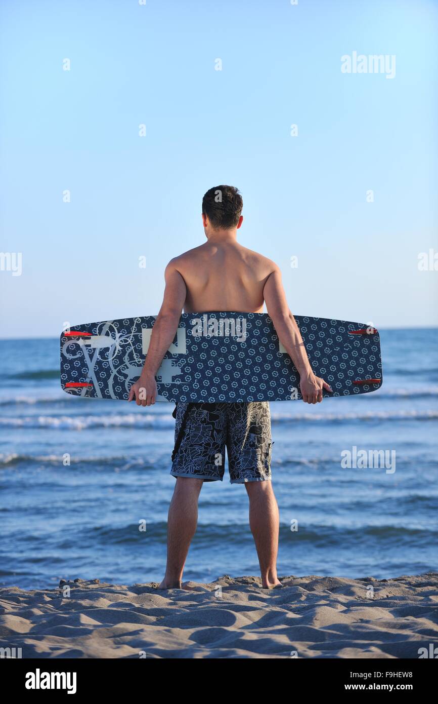 Portrait of a strong young surf man at beach on sunset in a ...