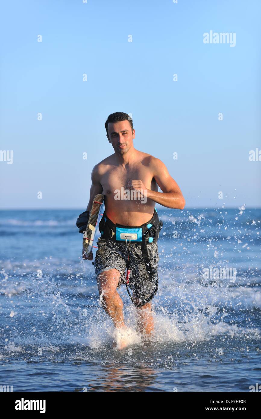 Portrait of a strong young surf man at beach on sunset in a ...