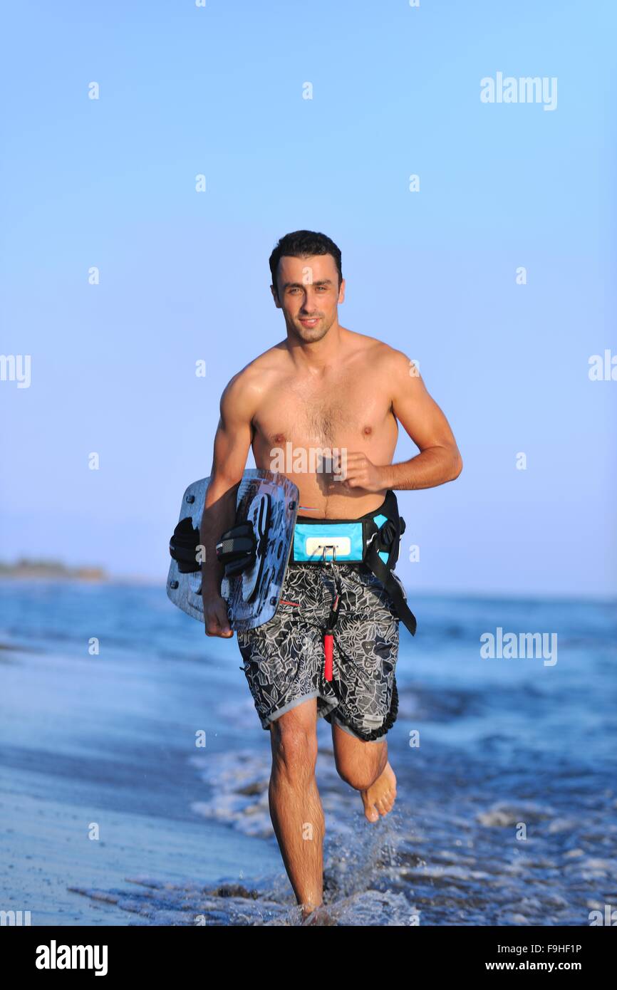 Portrait of a strong young surf man at beach on sunset in a ...