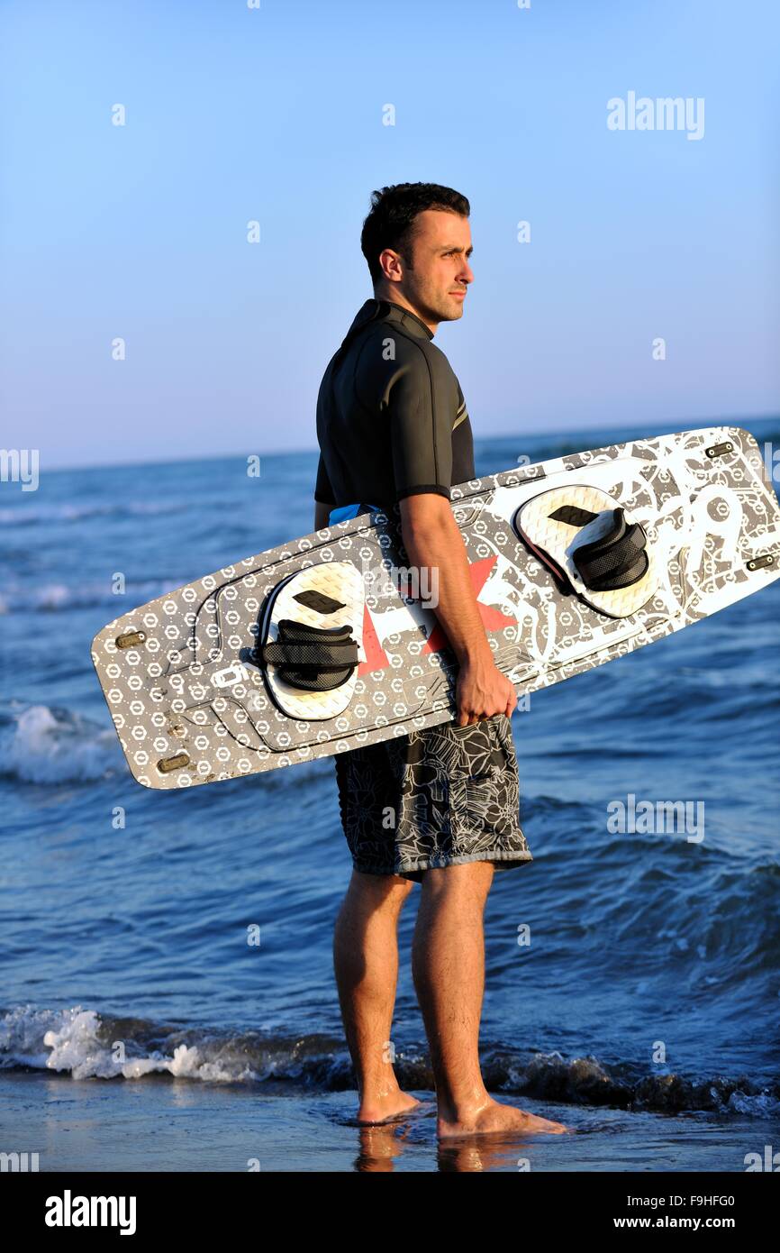 Portrait of a strong young surf man at beach on sunset in a ...