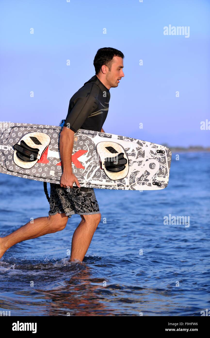 Portrait of a strong young surf man at beach on sunset in a ...