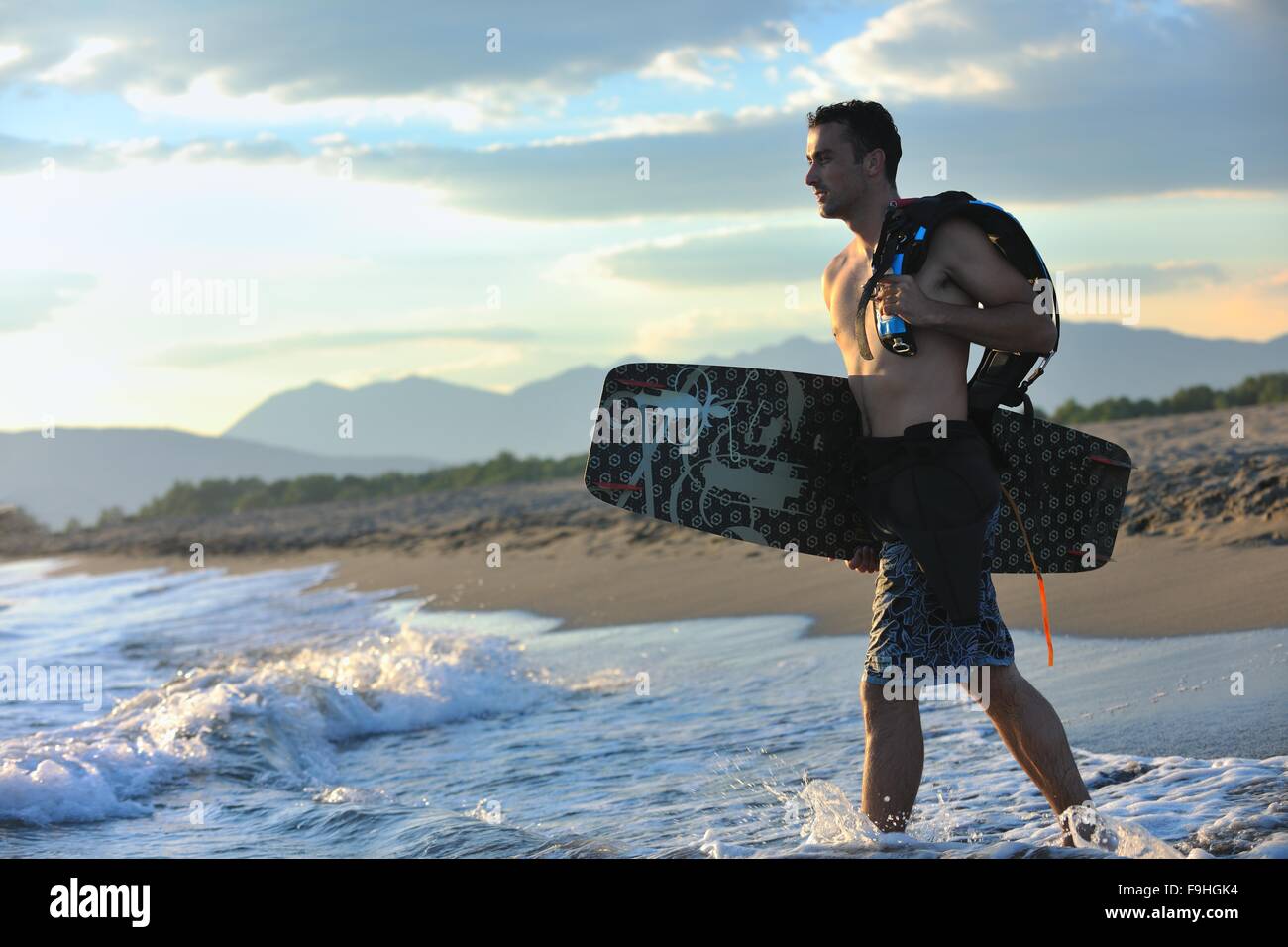 Portrait of a strong young surf man at beach on sunset in a ...