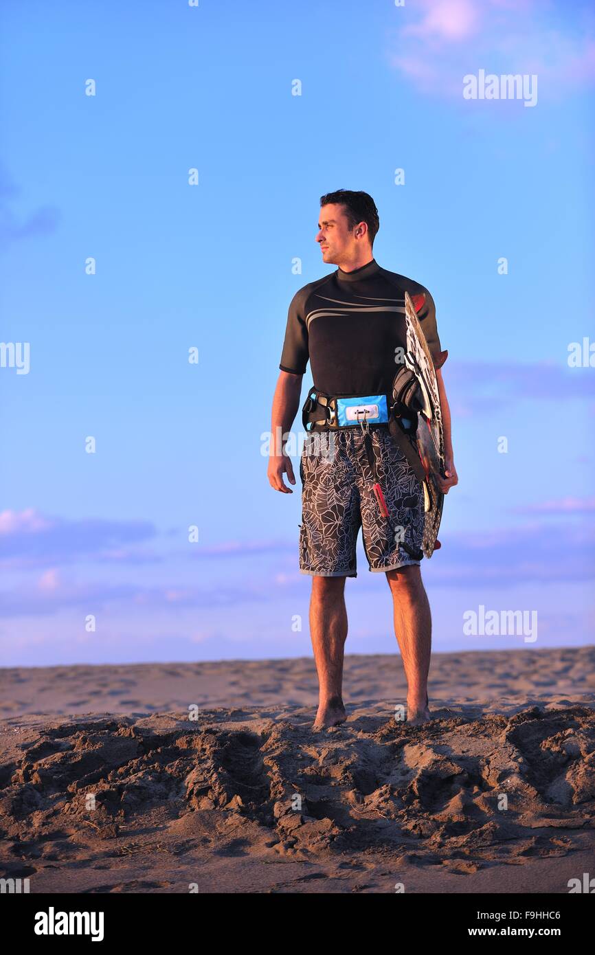 Portrait of a strong young surf man at beach on sunset in a ...