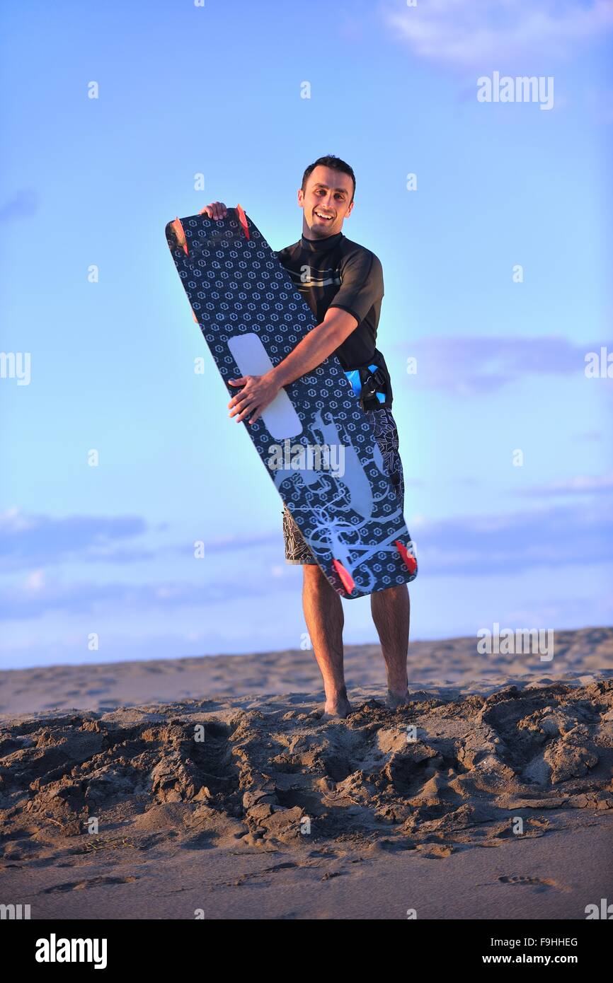 Portrait of a strong young surf man at beach on sunset in a ...