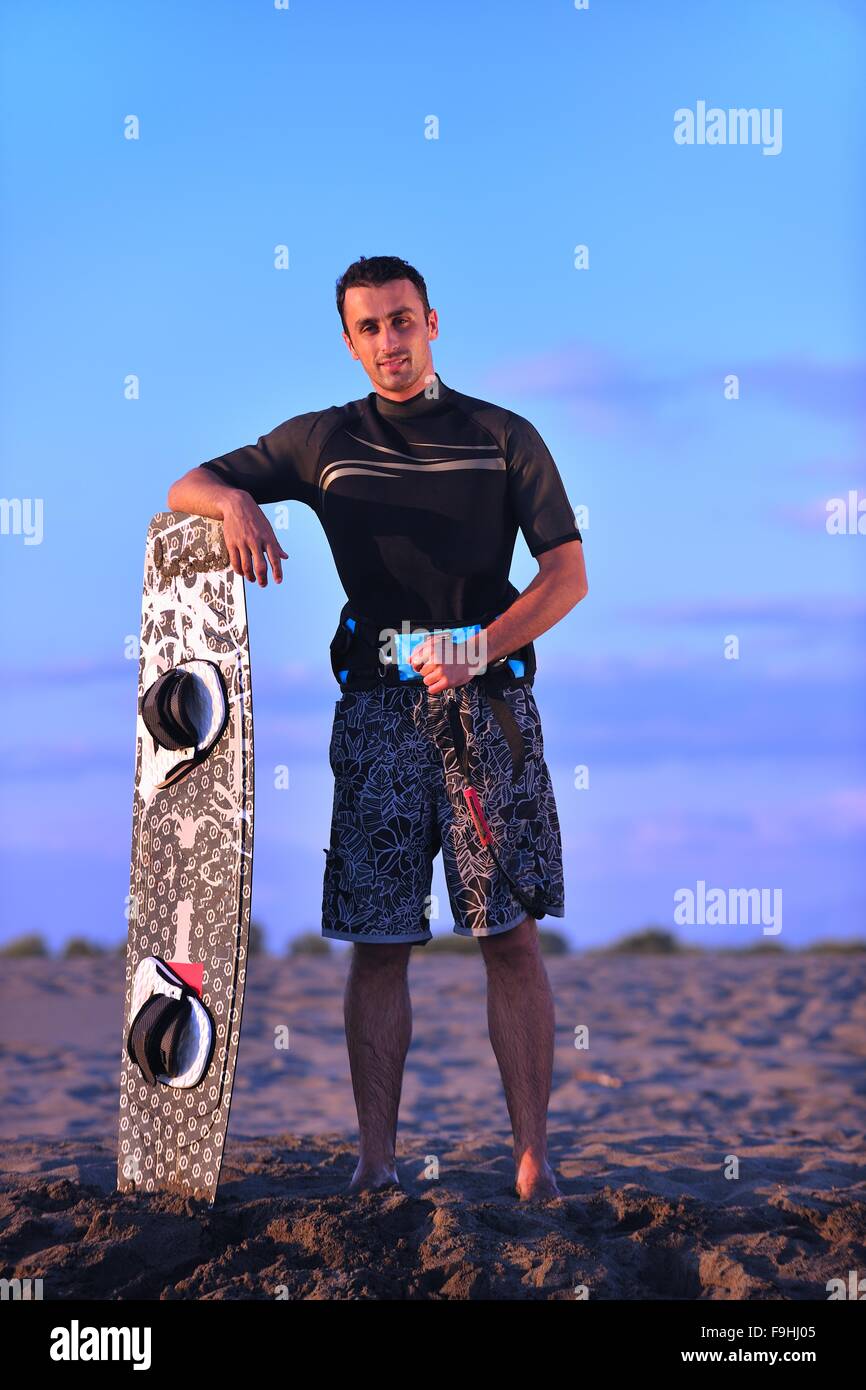 Portrait of a strong young surf man at beach on sunset in a ...