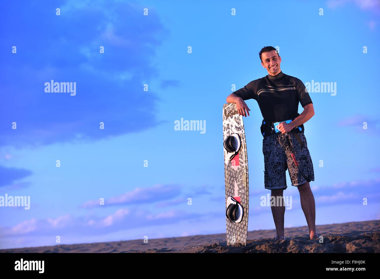 Portrait of a strong young surf man at beach on sunset in a ...