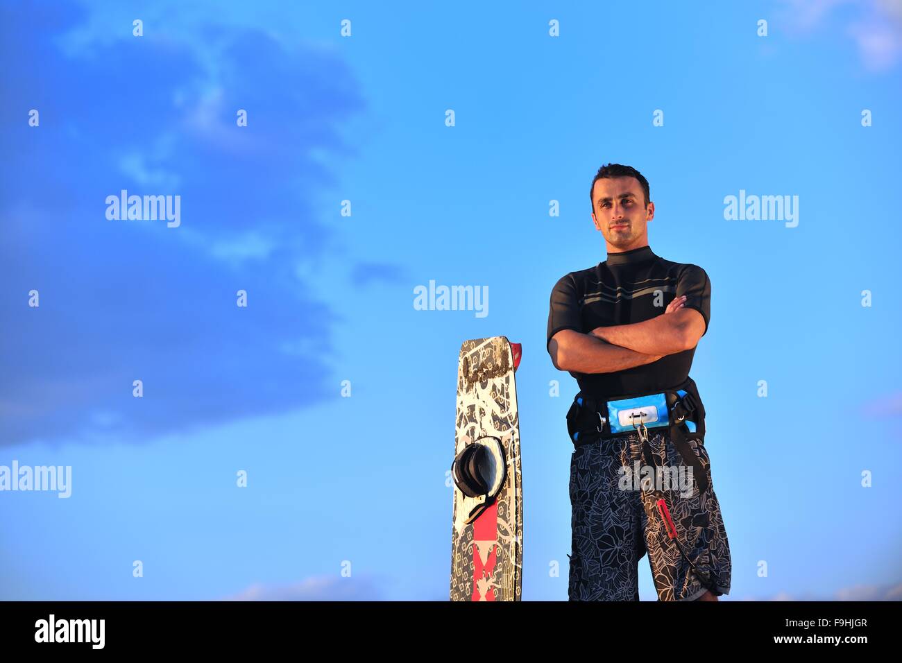 Portrait of a strong young surf man at beach on sunset in a ...