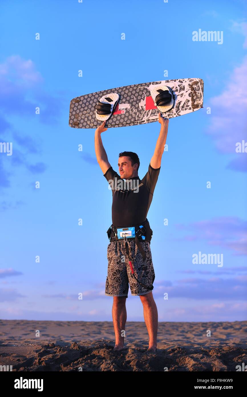 Portrait of a strong young surf man at beach on sunset in a ...