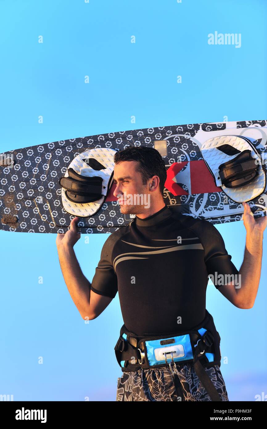 Portrait of a strong young surf man at beach on sunset in a ...