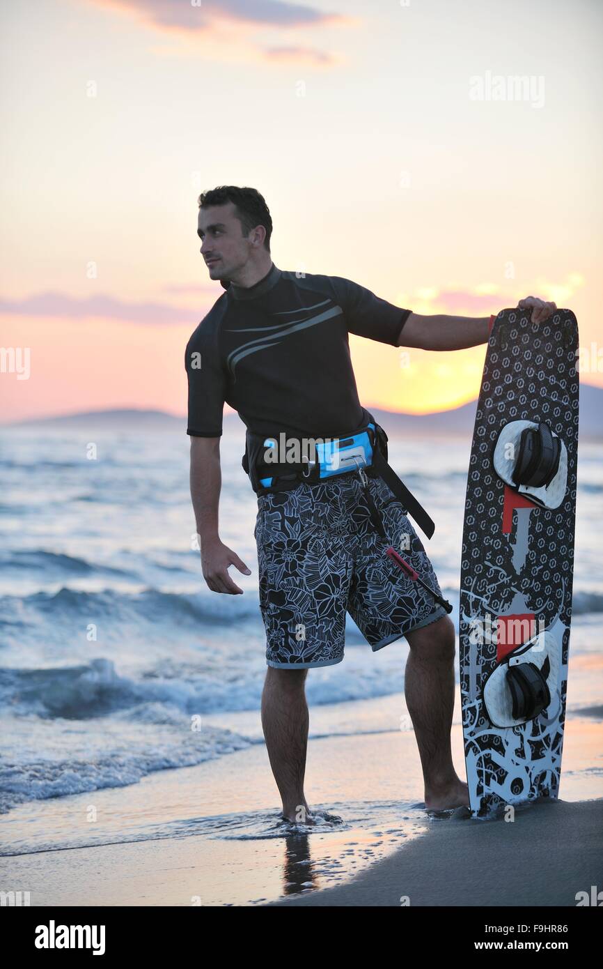 Portrait of a strong young surf man at beach on sunset in a ...