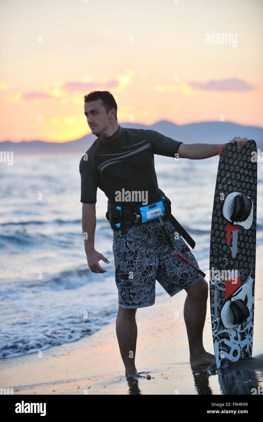Portrait of a strong young surf man at beach on sunset in a ...