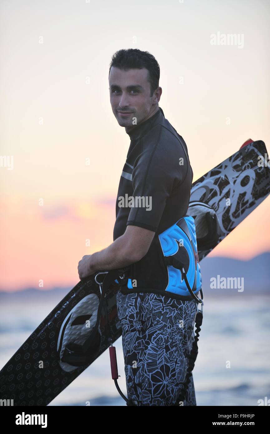 Portrait of a strong young surf man at beach on sunset in a ...