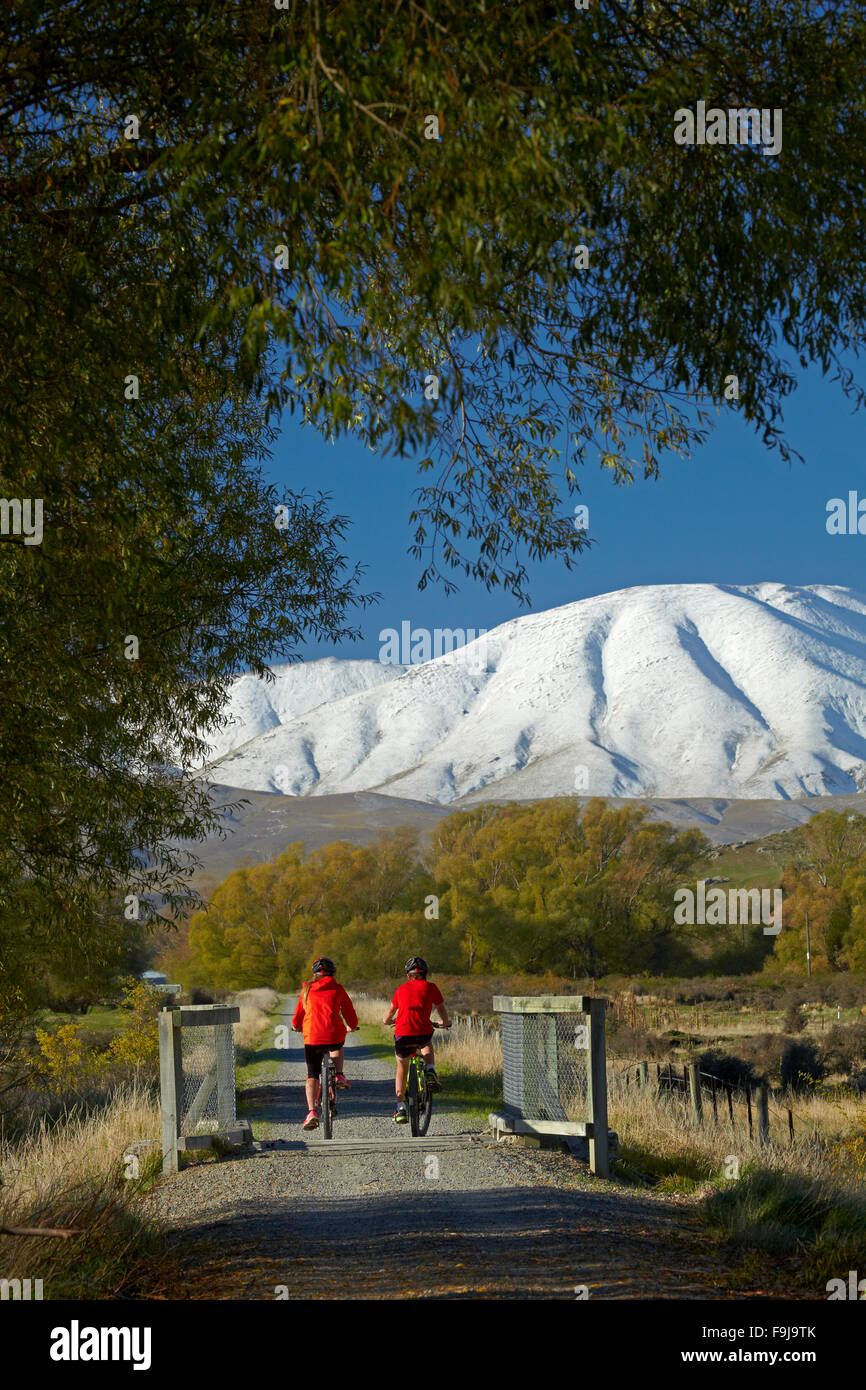 Cyclists on Otago Central Rail Trail in Ida Valley, and snow on Ida ...