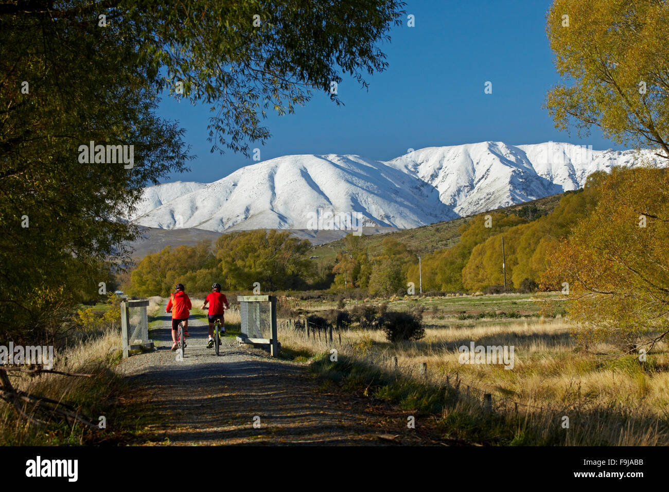 Cyclists on Otago Central Rail Trail in Ida Valley, and snow on Ida ...