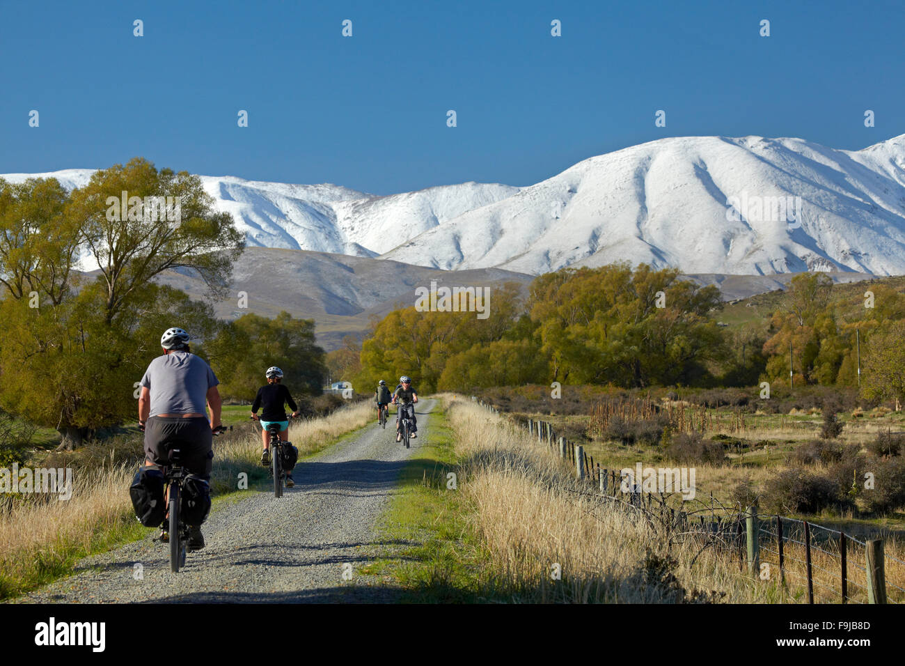 Cyclists on Otago Central Rail Trail in Ida Valley, and snow on Ida ...