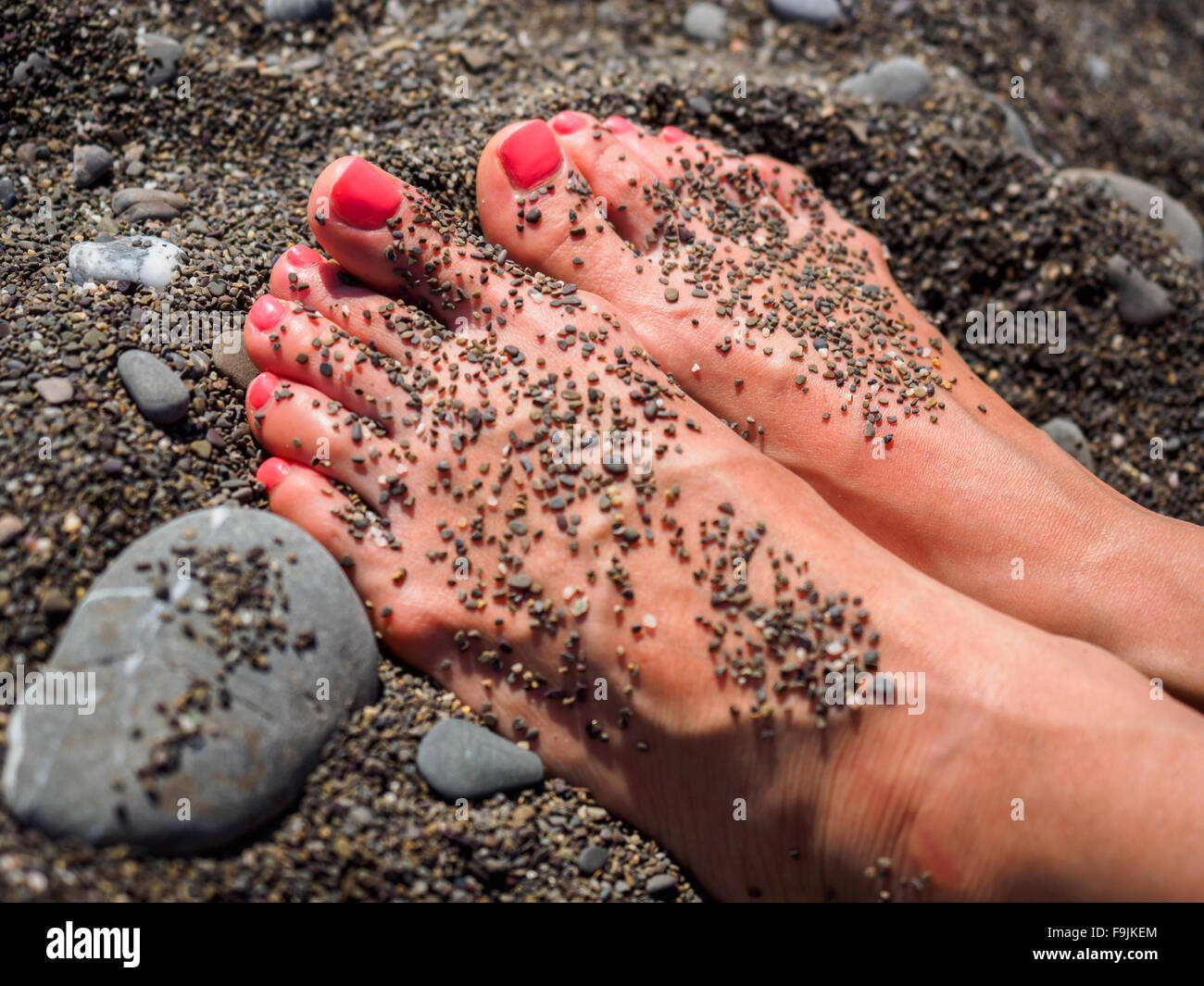 beach feet stuck with grains of sand on a beach on a sunny day with red ...