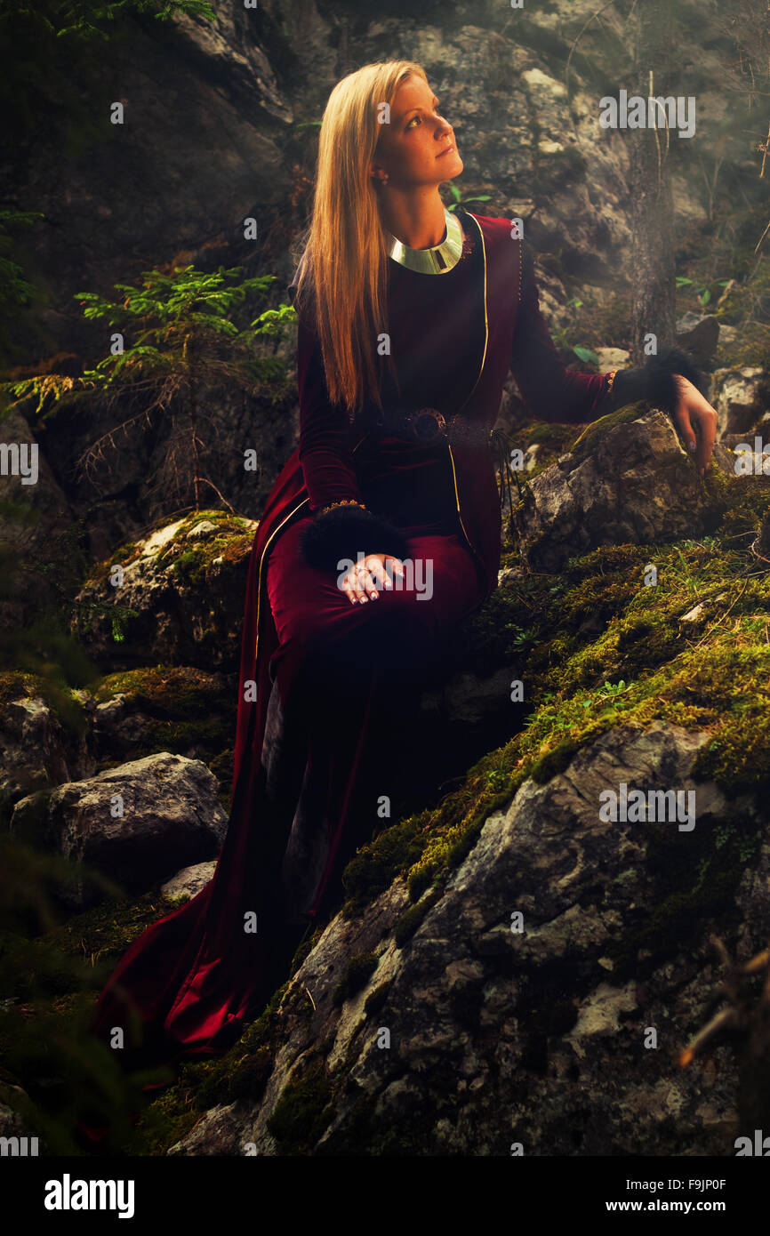 A beautiful woman fairy with long blonde hair in a historical gown is ...