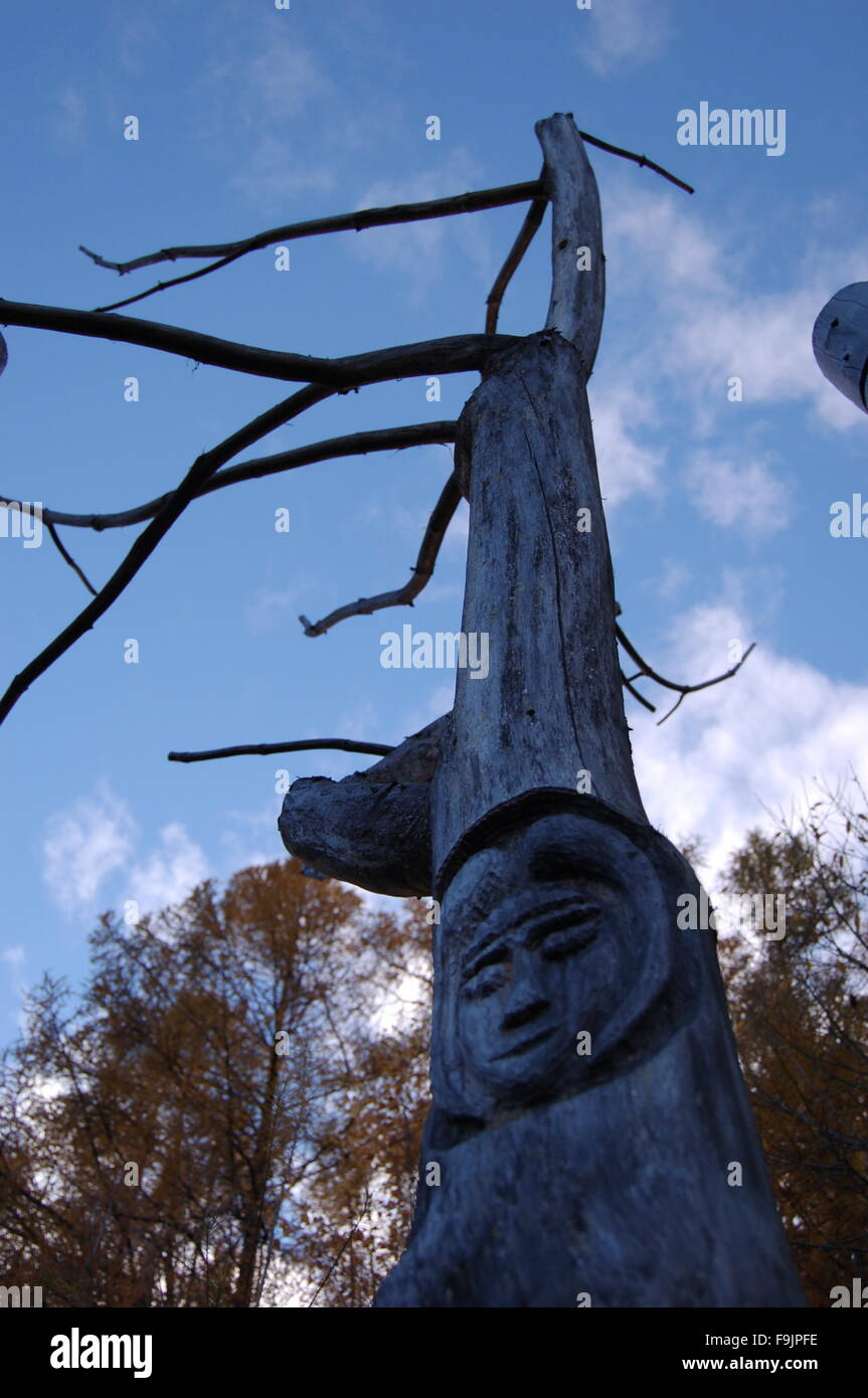 A totem face of a tree spirit carved on a tree trunk Stock Photo - Alamy