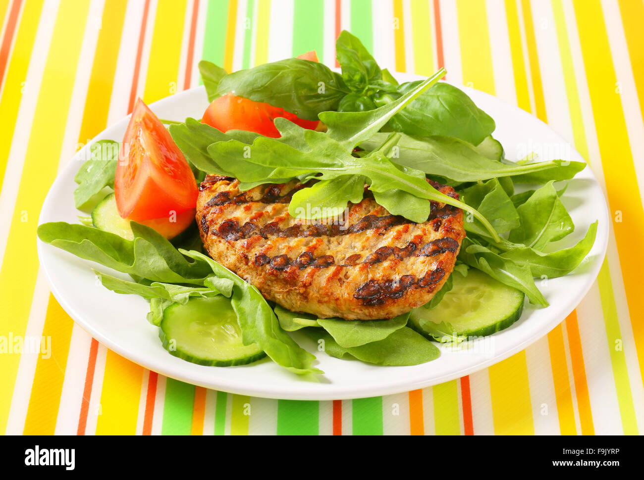 Grilled patty with rocket salad and sliced cucumber Stock Photo - Alamy