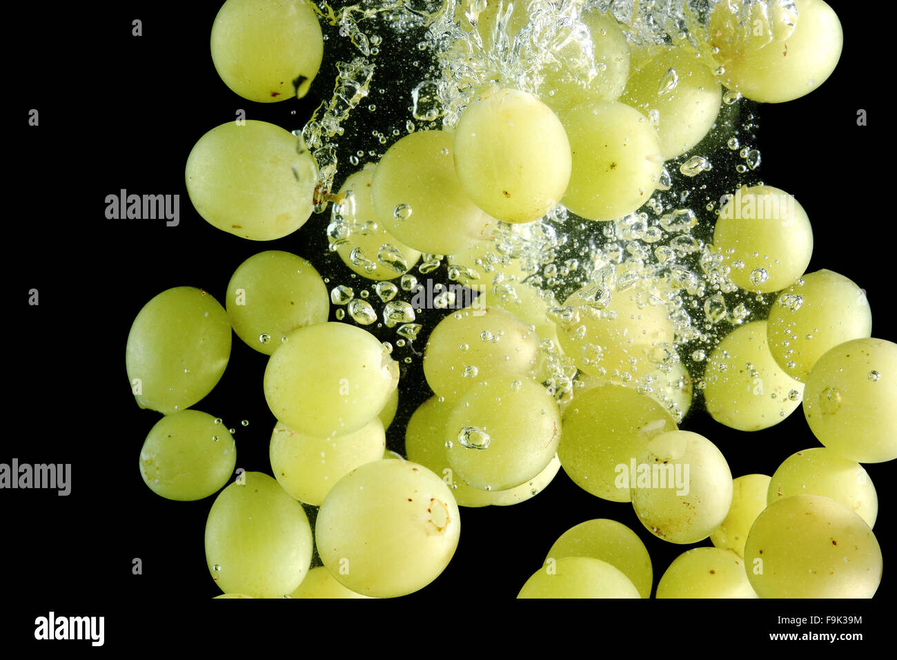 Green grape falling into water at black background Stock Photo - Alamy