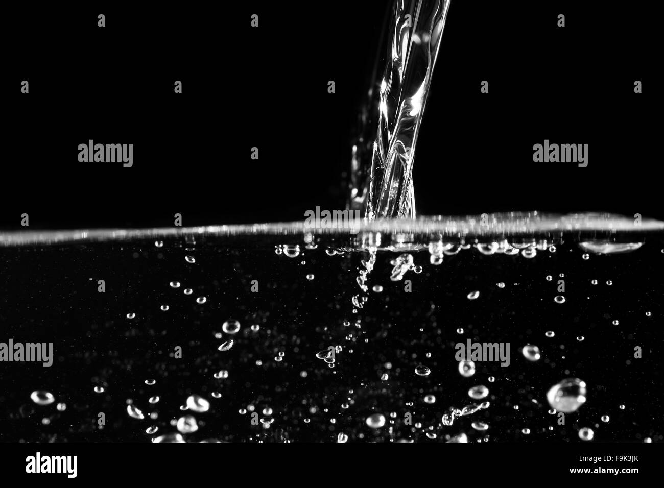 Stream of water pouring into water at black background. Close up Stock ...