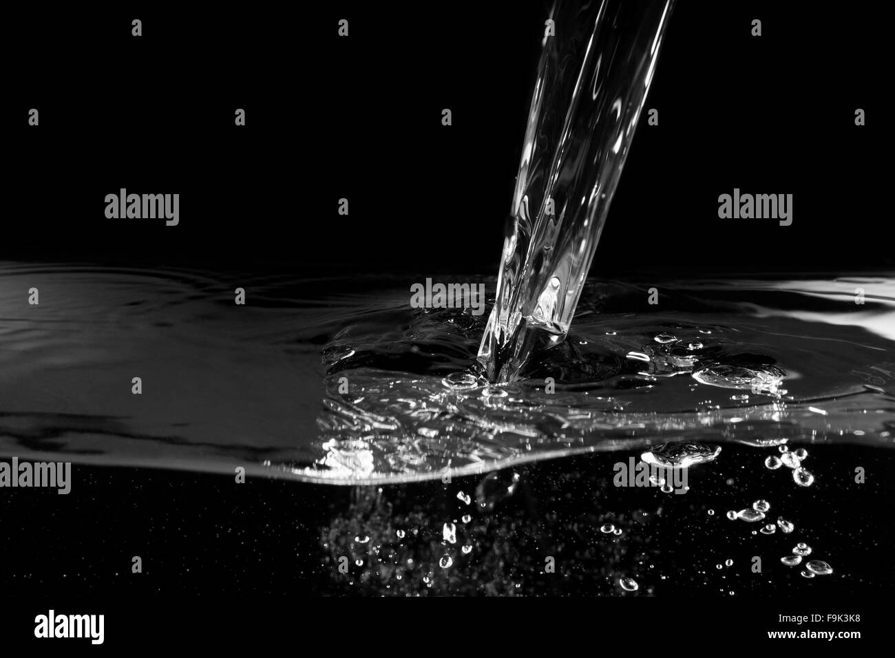 Stream of water pouring into water at black background. Close up Stock ...