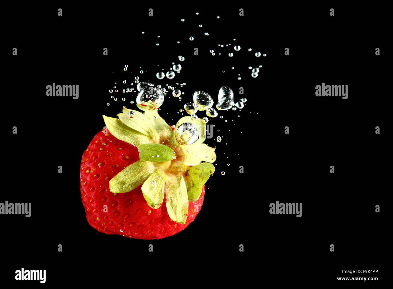 Strawberry falling into water at black background Stock Photo - Alamy