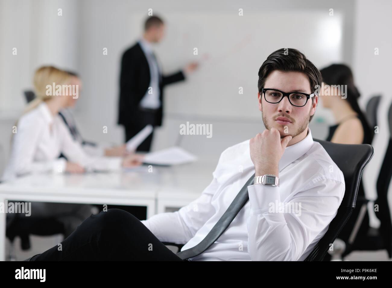 Portrait of a handsome young business man with people in background at ...