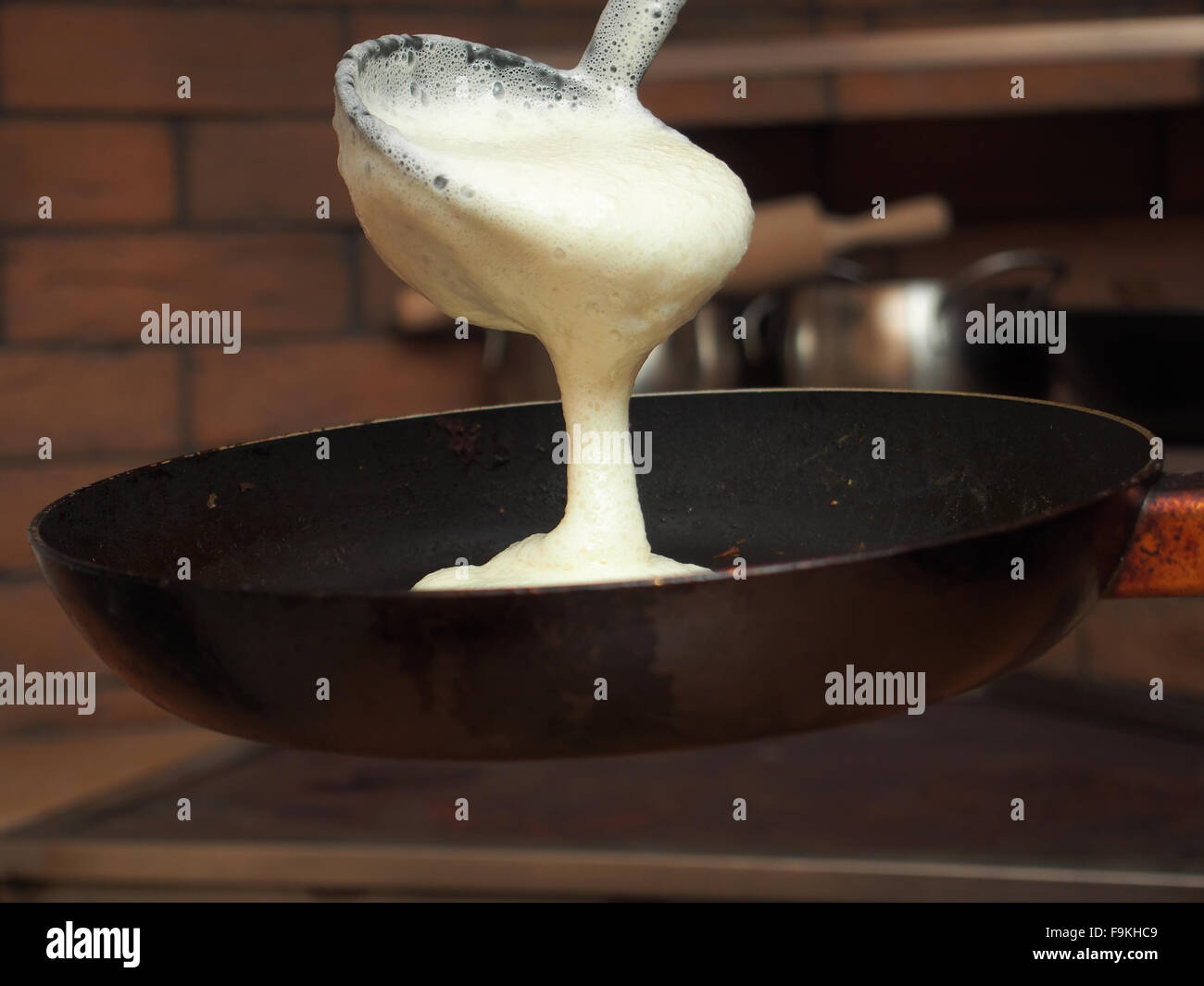 Pouring batter with a ladle. Making yeast pancakes (crepes Stock Photo ...