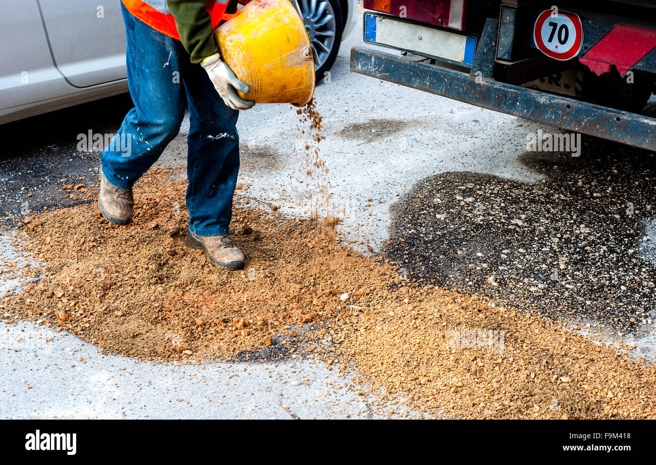 worker committed to the repair of a large pit road with inert mixed ...