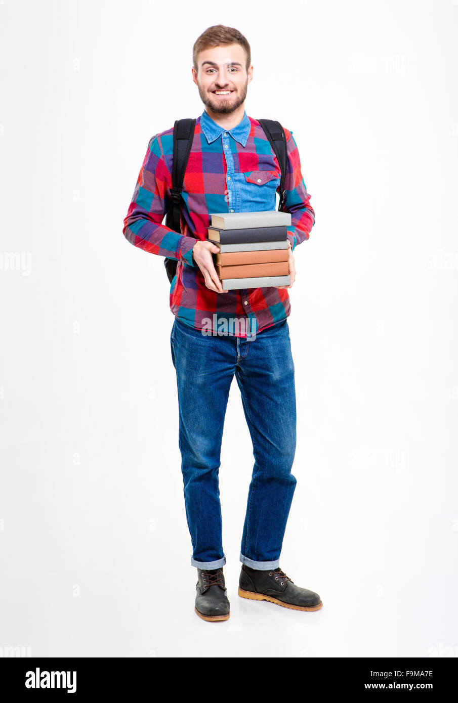 Full length portrait of a smiling male student holding books standing ...