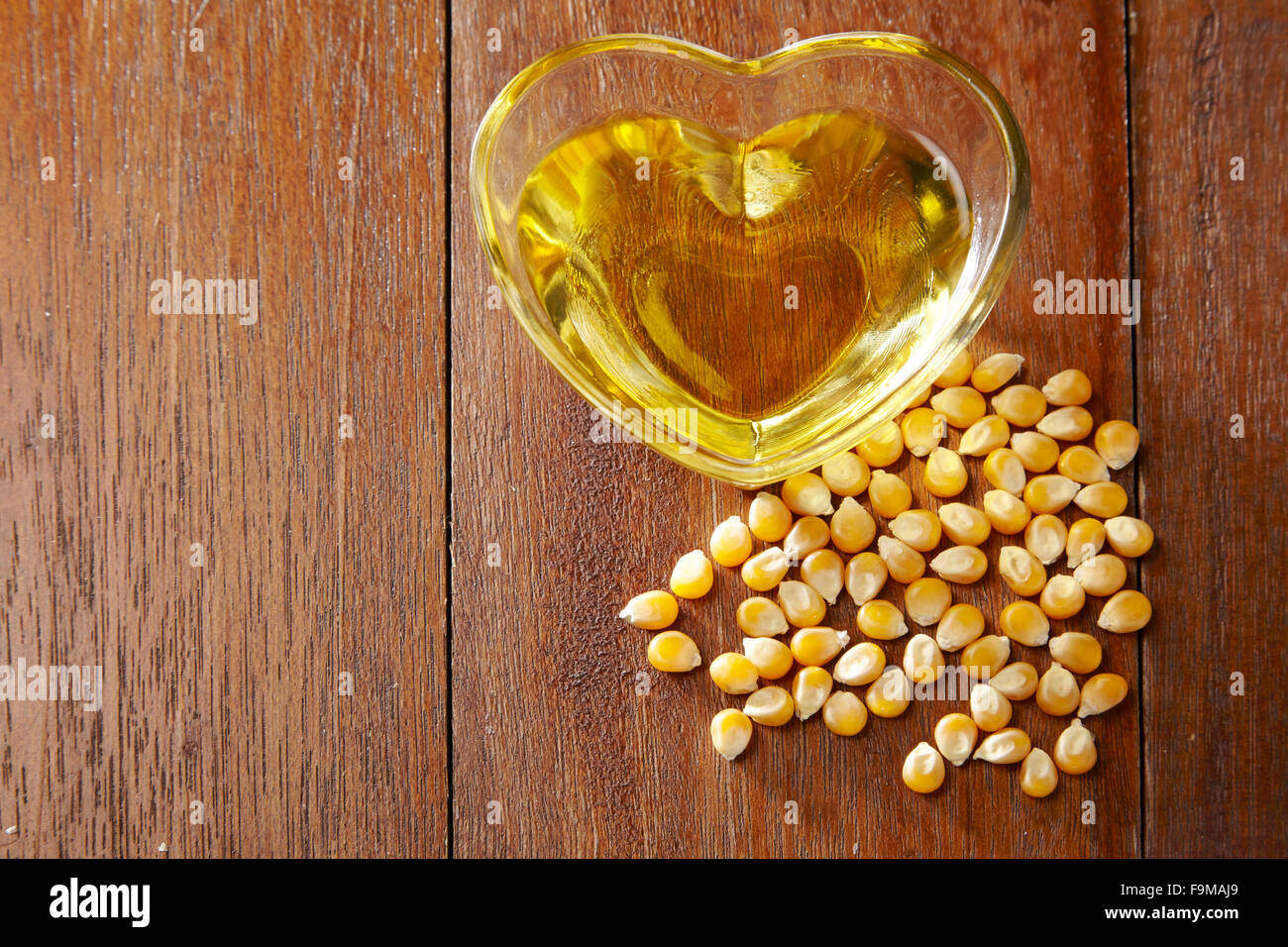 maize corn and glass of heart shape container filled up with corn oil ...