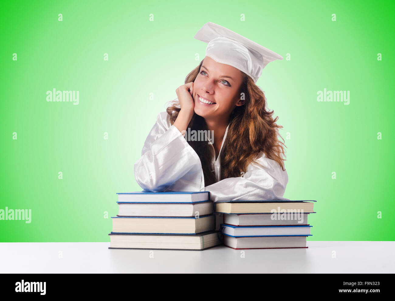 Happy graduate with lots of books on white Stock Photo - Alamy