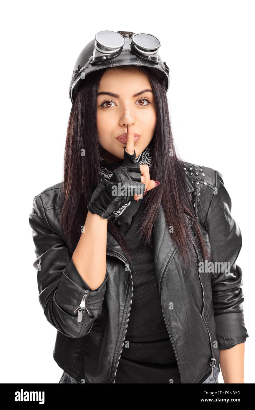 Vertical shot of a female biker holding a finger on her lips and ...