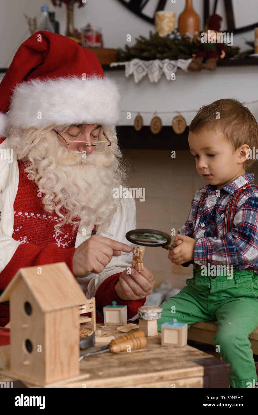 Santa Claus With Child Making Christmas Gifts And Toys At Home Stock