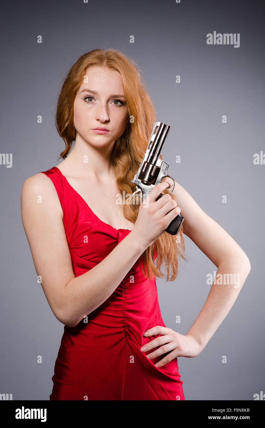 Girl in red dress with handgun against gray Stock Photo - Alamy